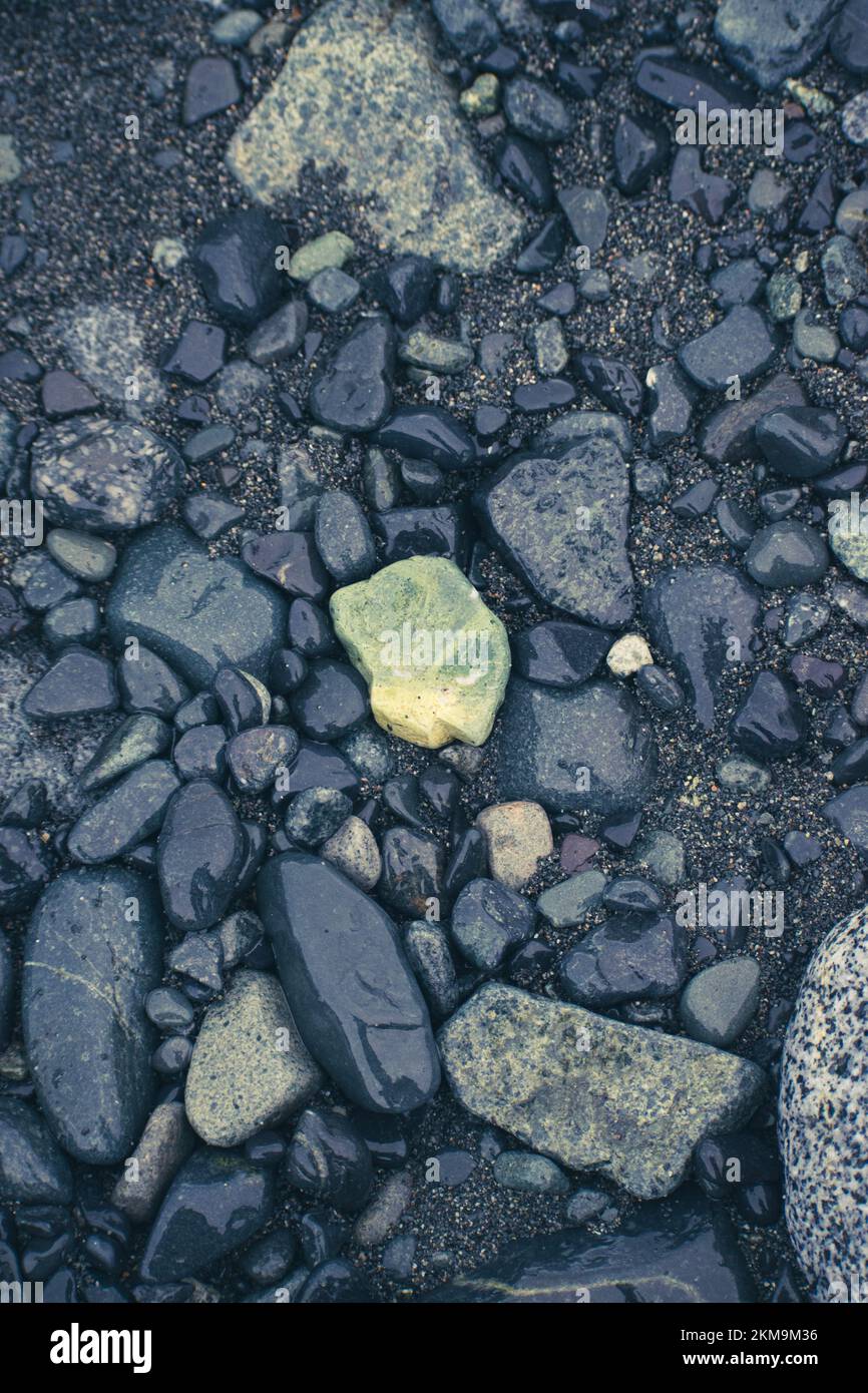 A close-up of a brightly colored rock among dark-colored rocks on an ...