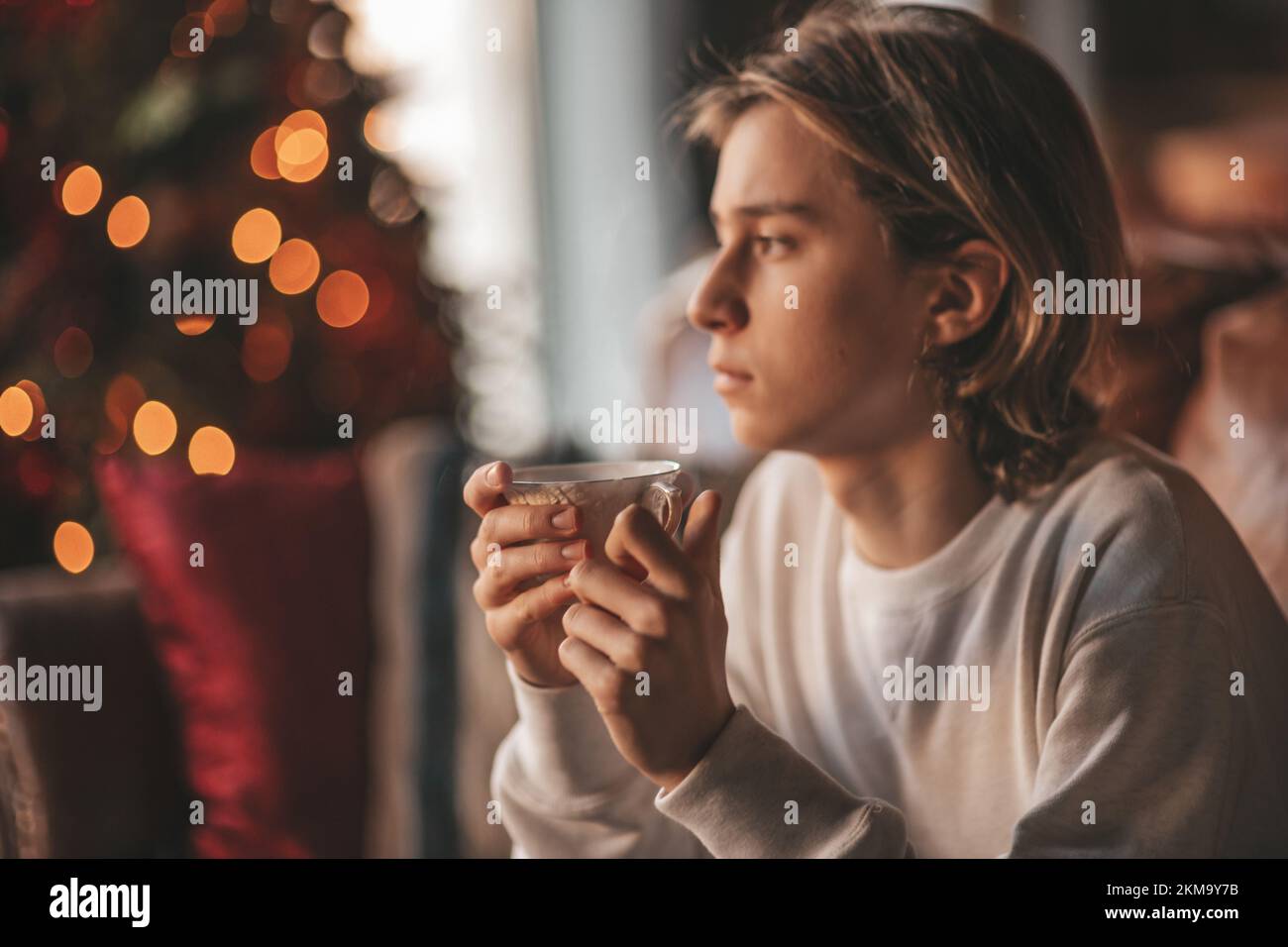 Young teen boy with long hair thoughtful look sad eyes negative mood ...