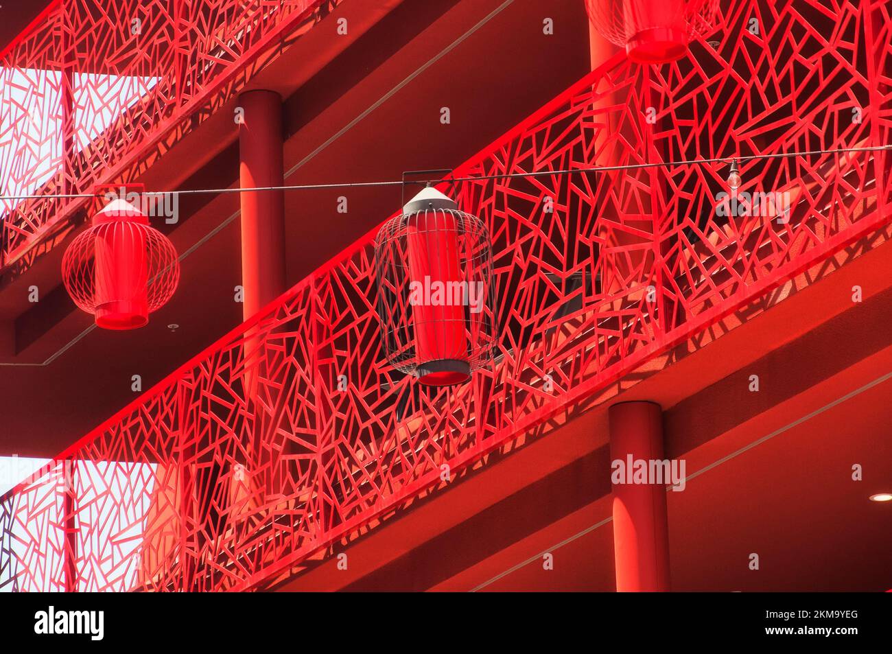 A red building exterior and red lanterns hanging from wires near the ...