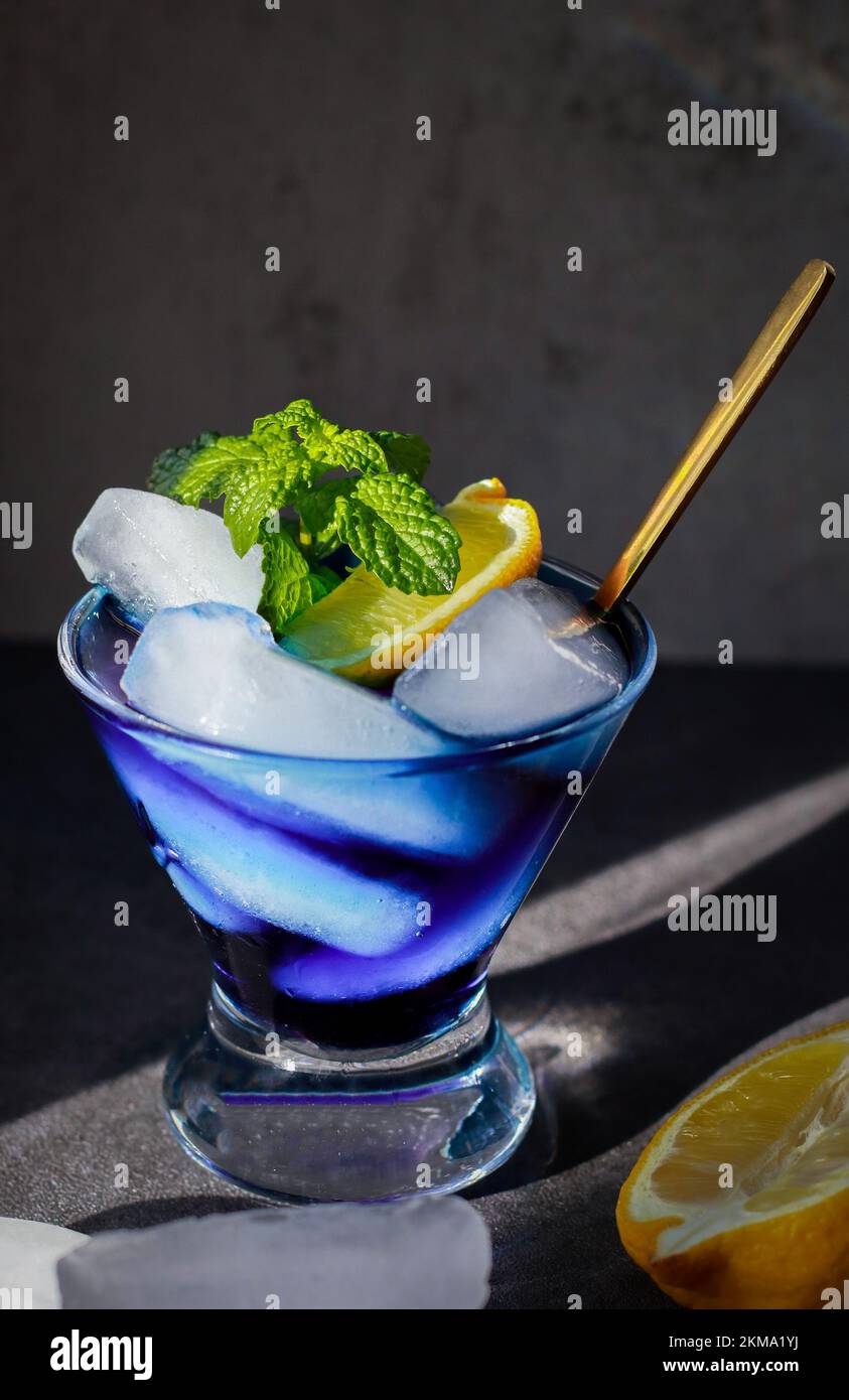 Close up of blue lagoon cocktail with ice, mint and lemon, grey ...