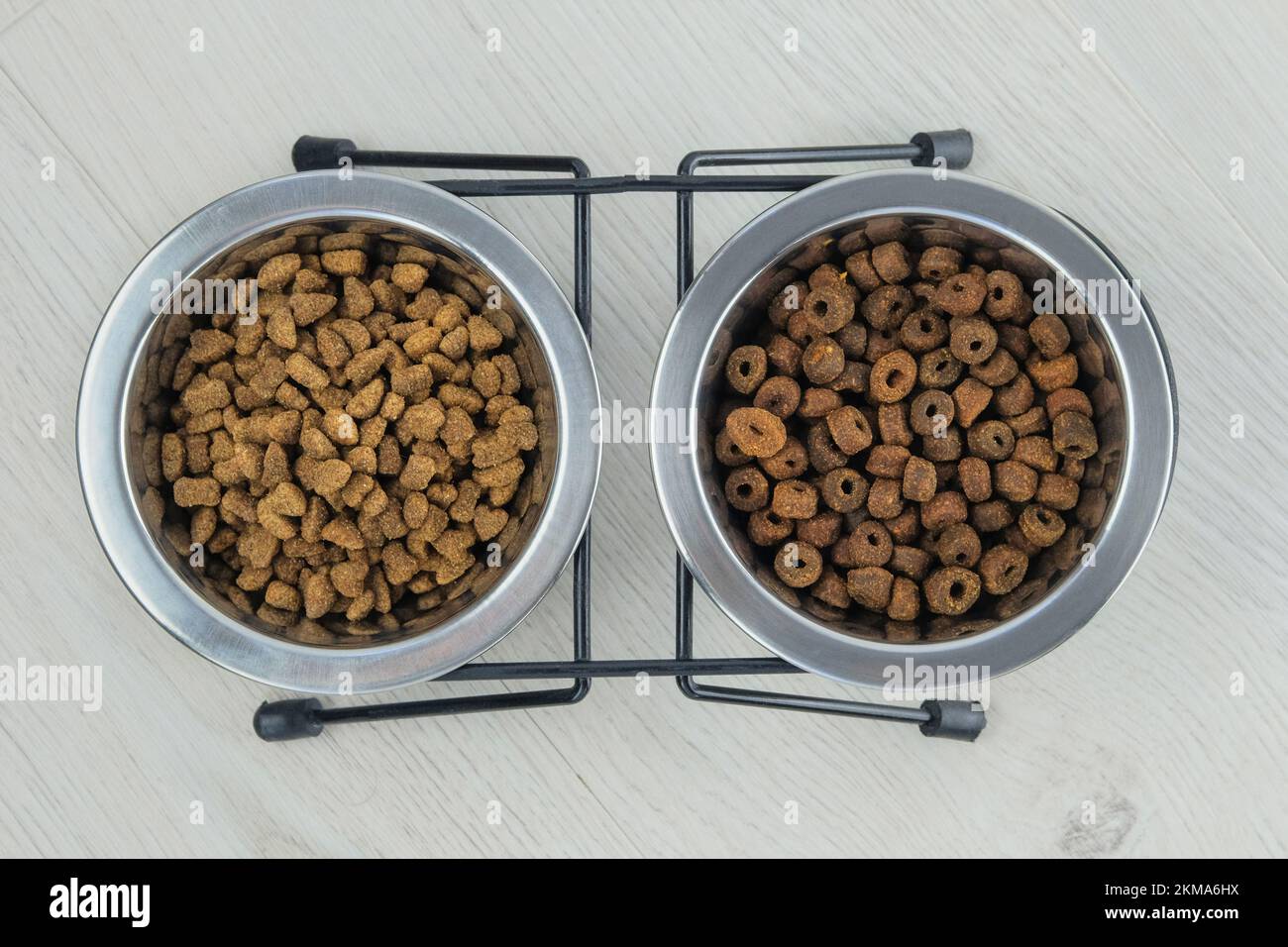 Dry food for cats and dogs in metal bowls on a white wooden background ...