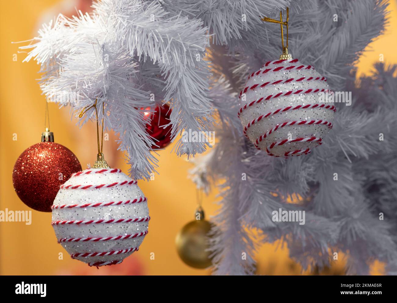 Red and white Christmas balls hanging from a branch of a white ...