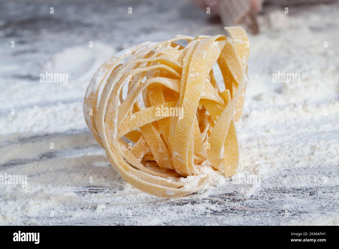 wheat flour pasta and wheat flour on a board, dry uncooked noodles with ...