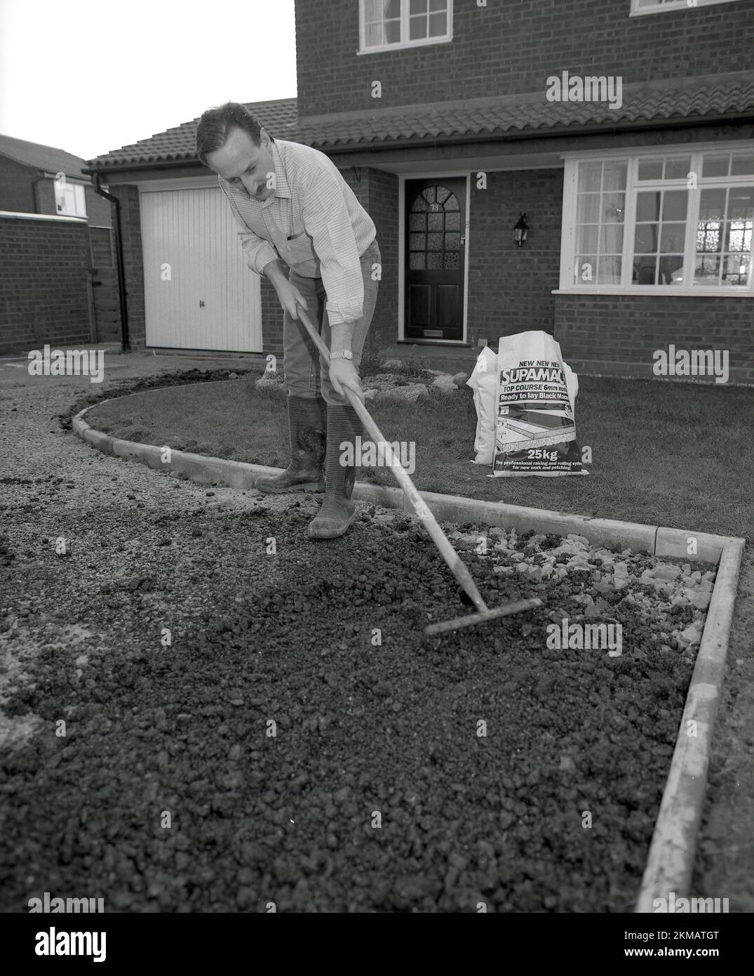1980s, outside the front of a detached house, a man re-surfacing a ...