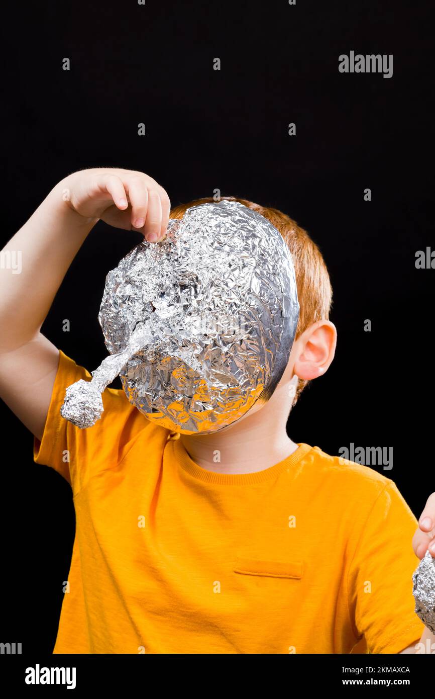 a beautiful red-haired boy with a homemade foil hat, the boy plays with ...