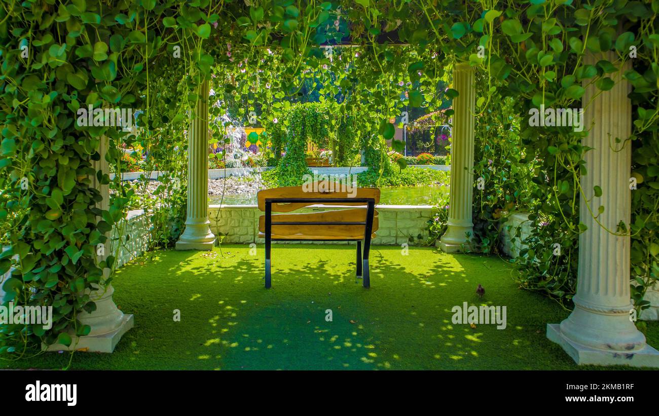 A single bench facing backwards inside an outdoor structure in a park ...