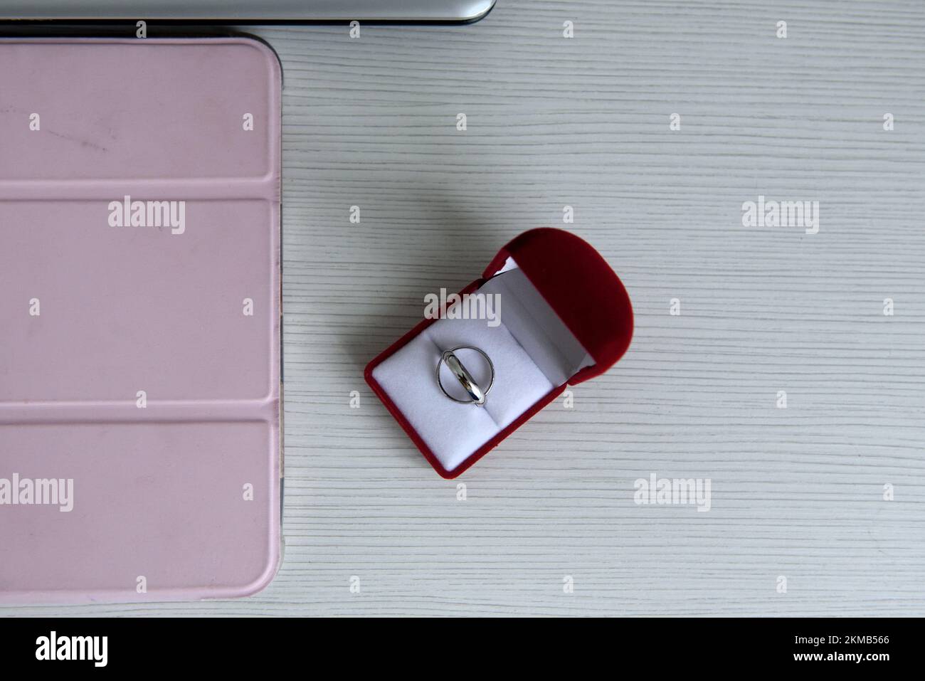 A top view of wedding rings in a small red box on the table next to a ...