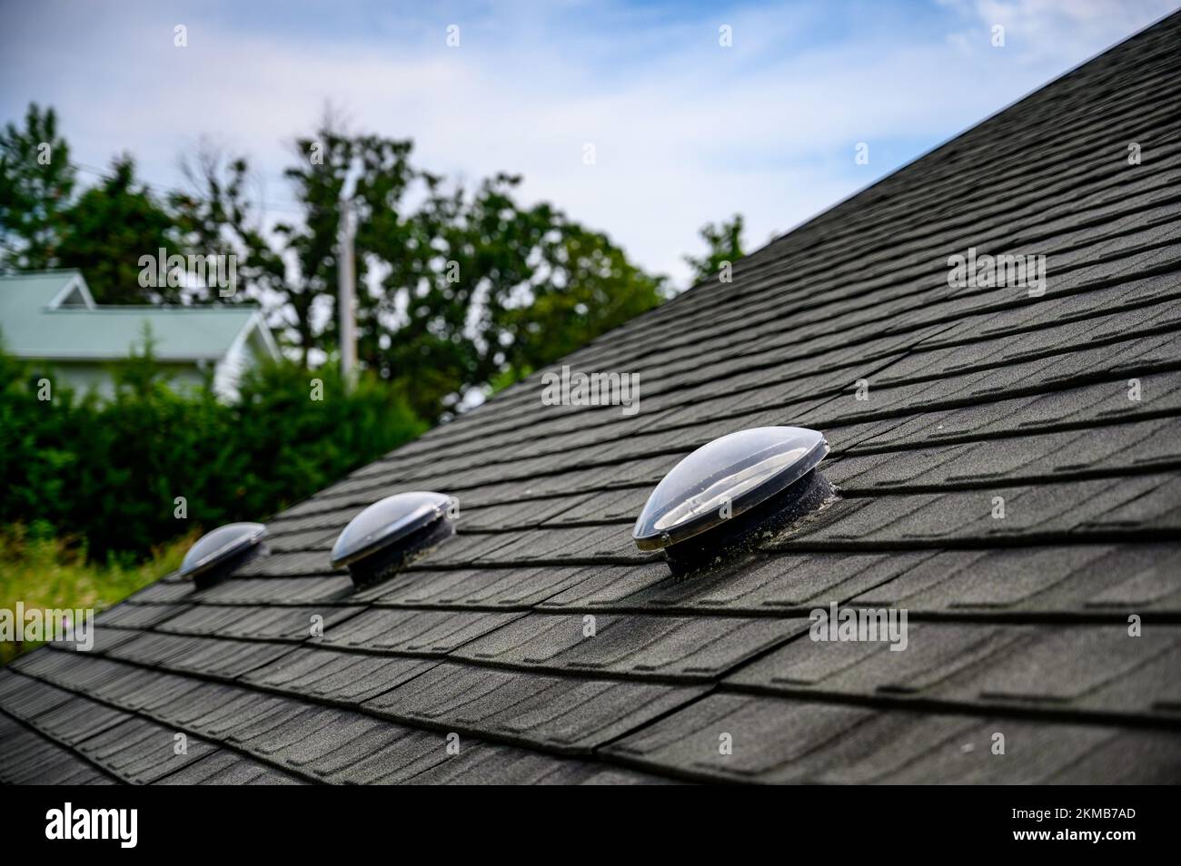 Dome shaped solar tube skylight on asphalt shingle roof Stock Photo - Alamy