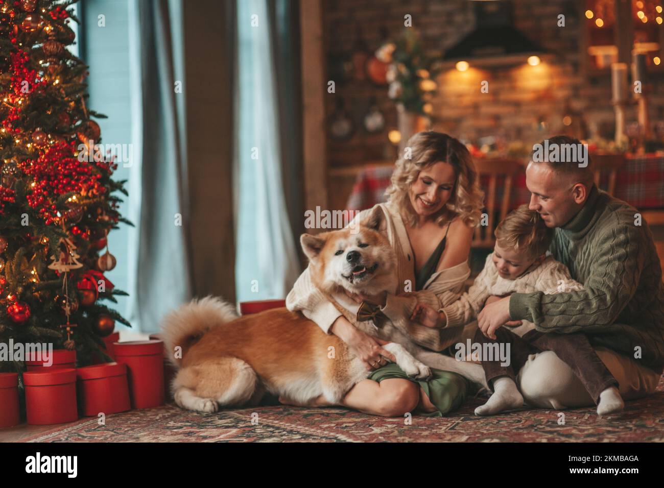 Portrait of happy family in knitted beige sweaters waiting Santa indoor ...