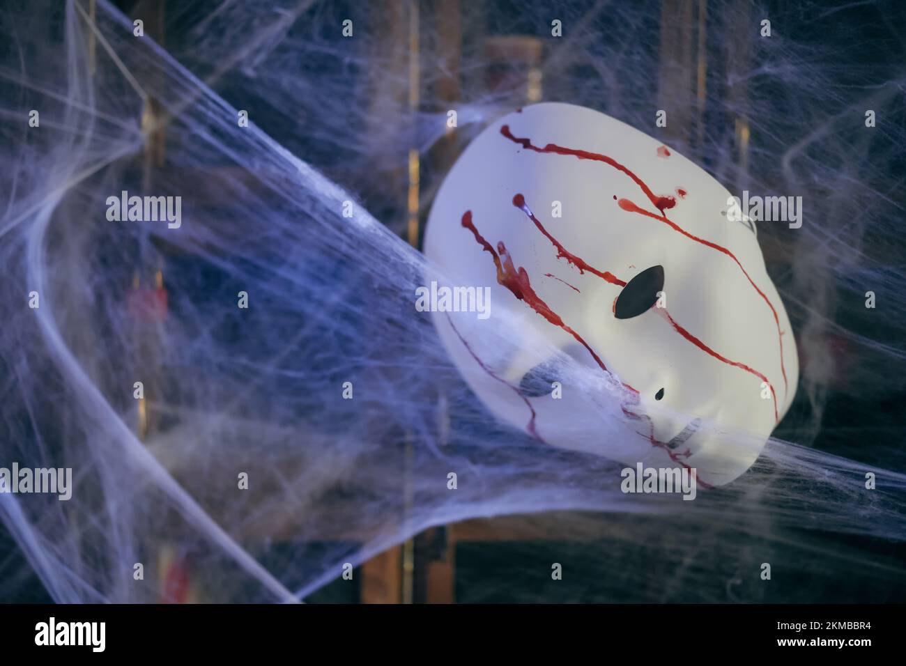 Color image of a white mask, painted with blood, in some spiderwebs and ...