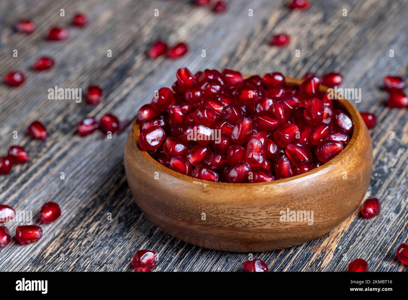 scattered pomegranate seeds on a wooden board, red ripe pomegranate ...