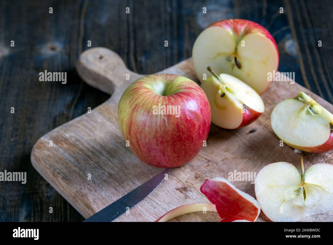 sliced ripe red juicy apple, cutting old board with pieces of red ripe ...
