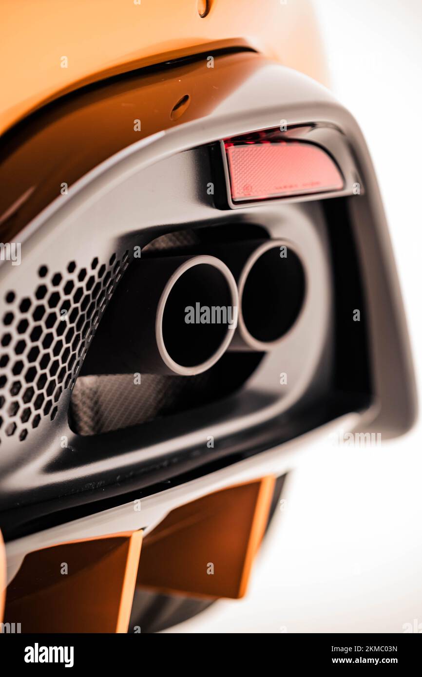 A vertical closeup of an Aston Martin Vantage exhaust pipes on a Golden Saffron background Stock ...