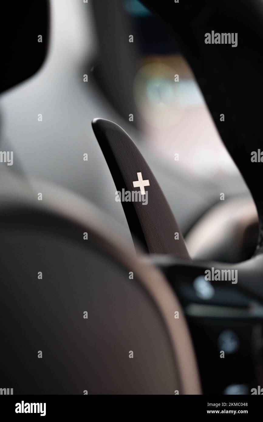 A vertical closeup of a black steering wheel pedal shift with a cross ...