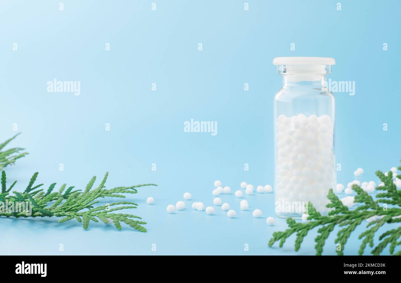 Homeopathic globules and glass bottle near with fresh juniper branches ...