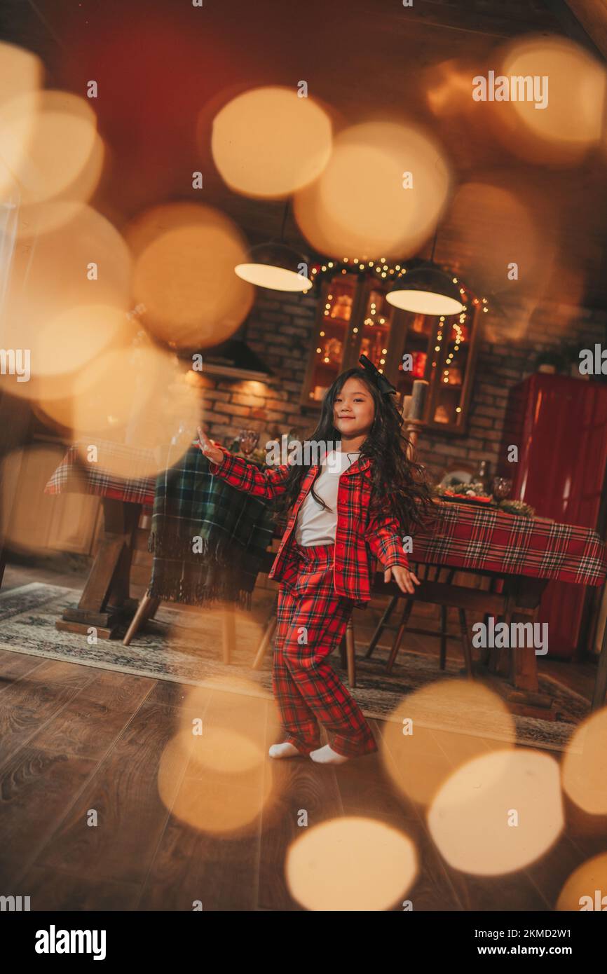 Active japan kid girl with stylish long brunette hair model pose at home in bokeh garlands noel ...