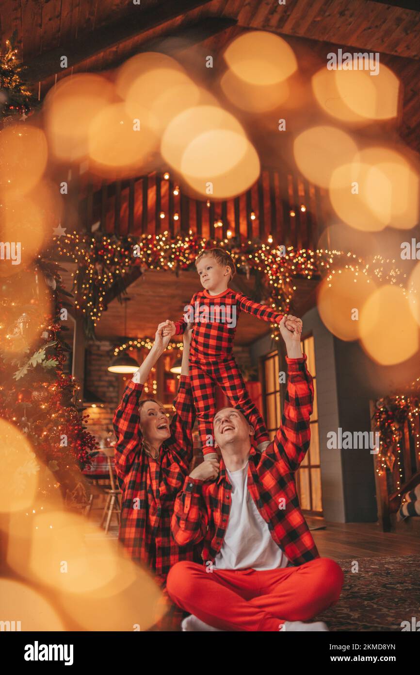 Smile active parents with small son in red checkered sleepwears waiting ...