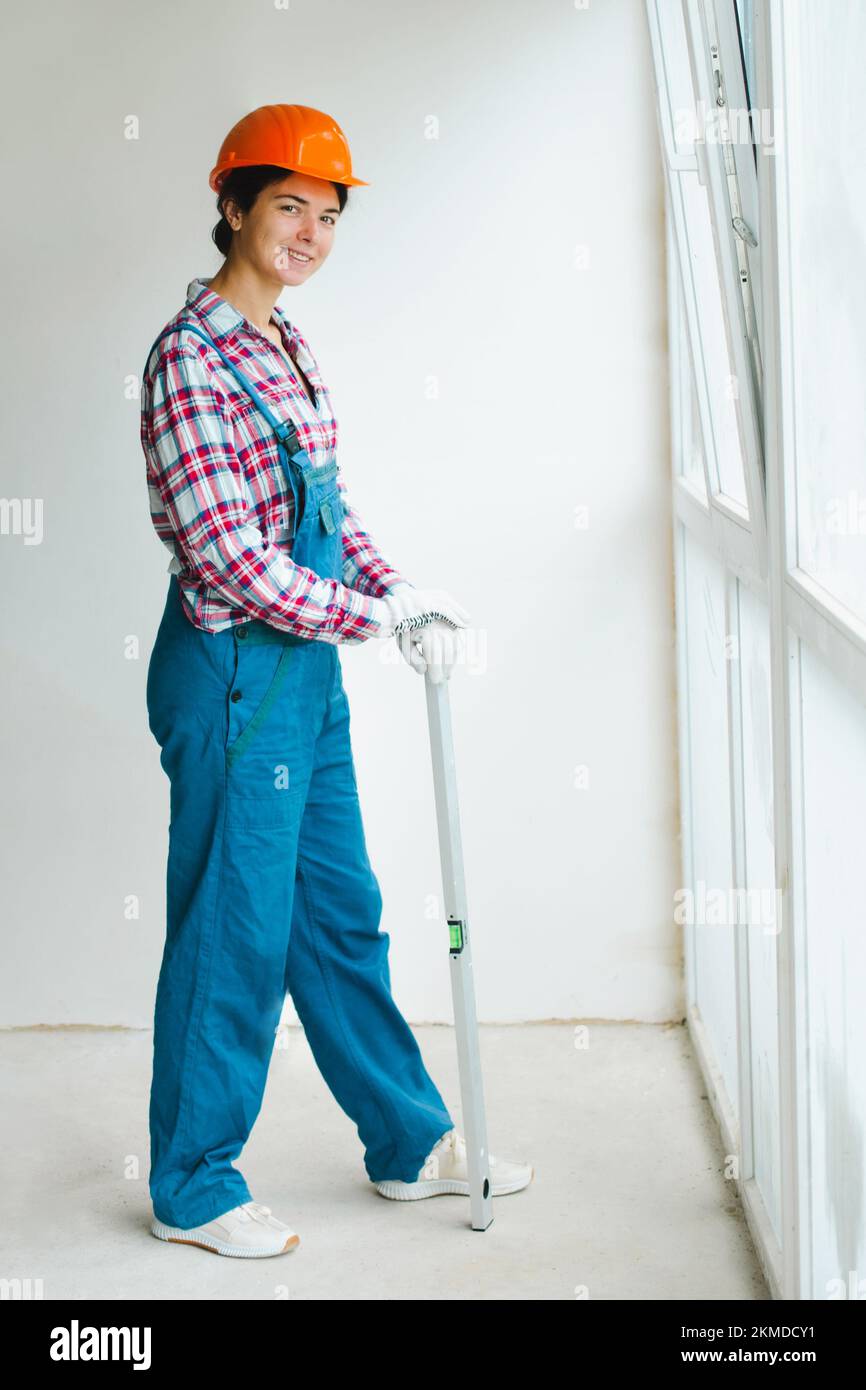 woman in blue overalls as construction worker hold level standing near ...
