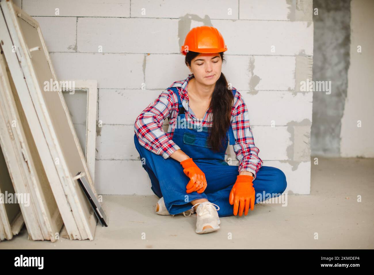 tired woman construction worker sit on concrete floor after hard work ...
