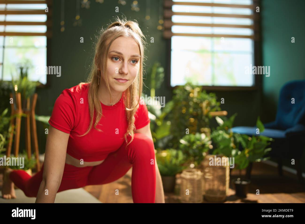 modern woman in red fitness clothes at modern green home doing yoga ...