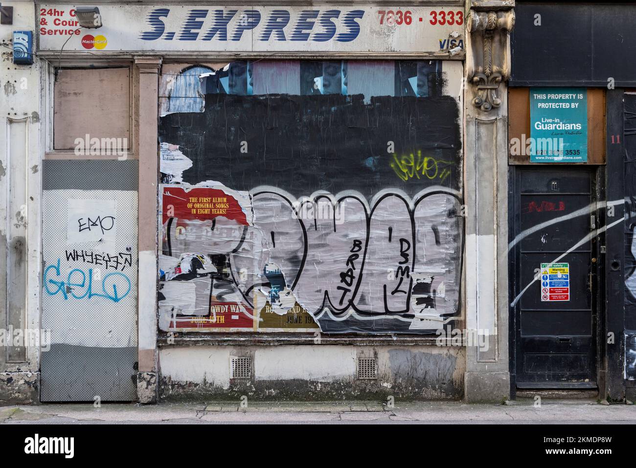 A closed down shop with its windows boarded up and covered with ...