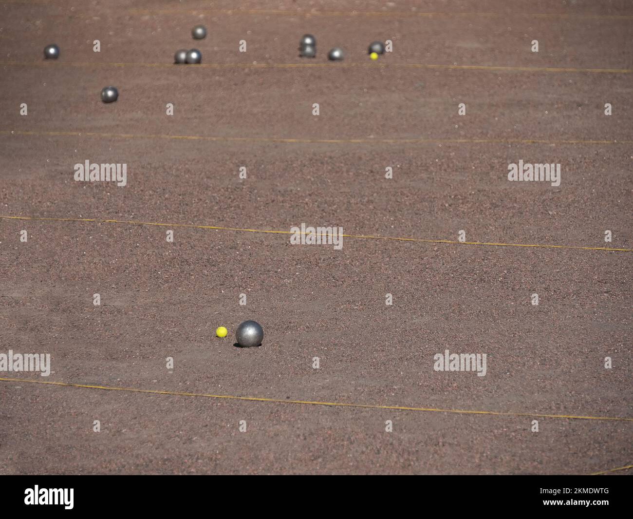 Metallic petanque balls and a small yellow jack on a sand court Stock ...