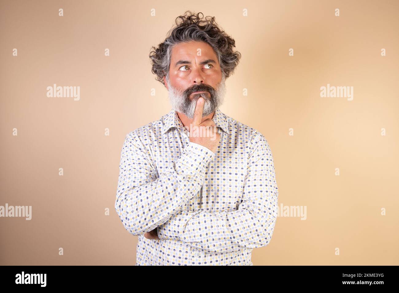 A middle-aged grey-haired man in casual clothes with a finger on his ...