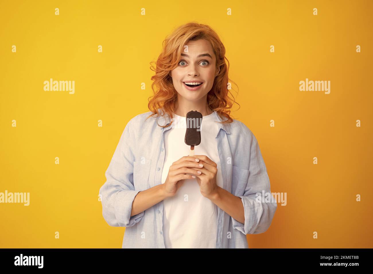 Young woman eat ice creams with chocolate glaze on yellow background ...