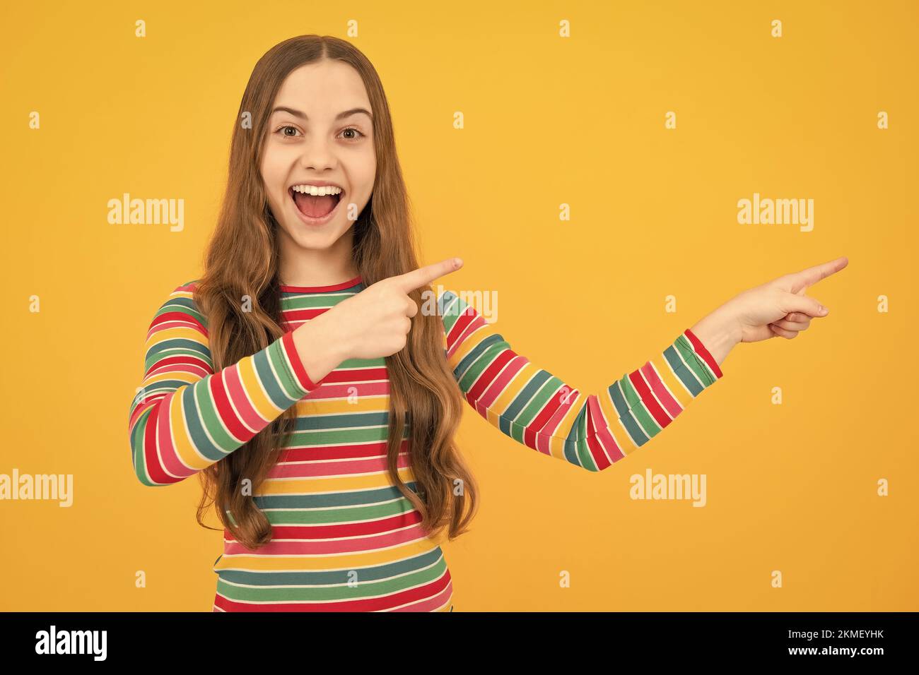 Portrait of cute teenager child girl pointing hand showing adverts with ...