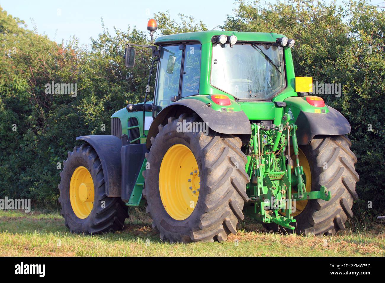 Large green tractor standing in a farm field Stock Photo - Alamy