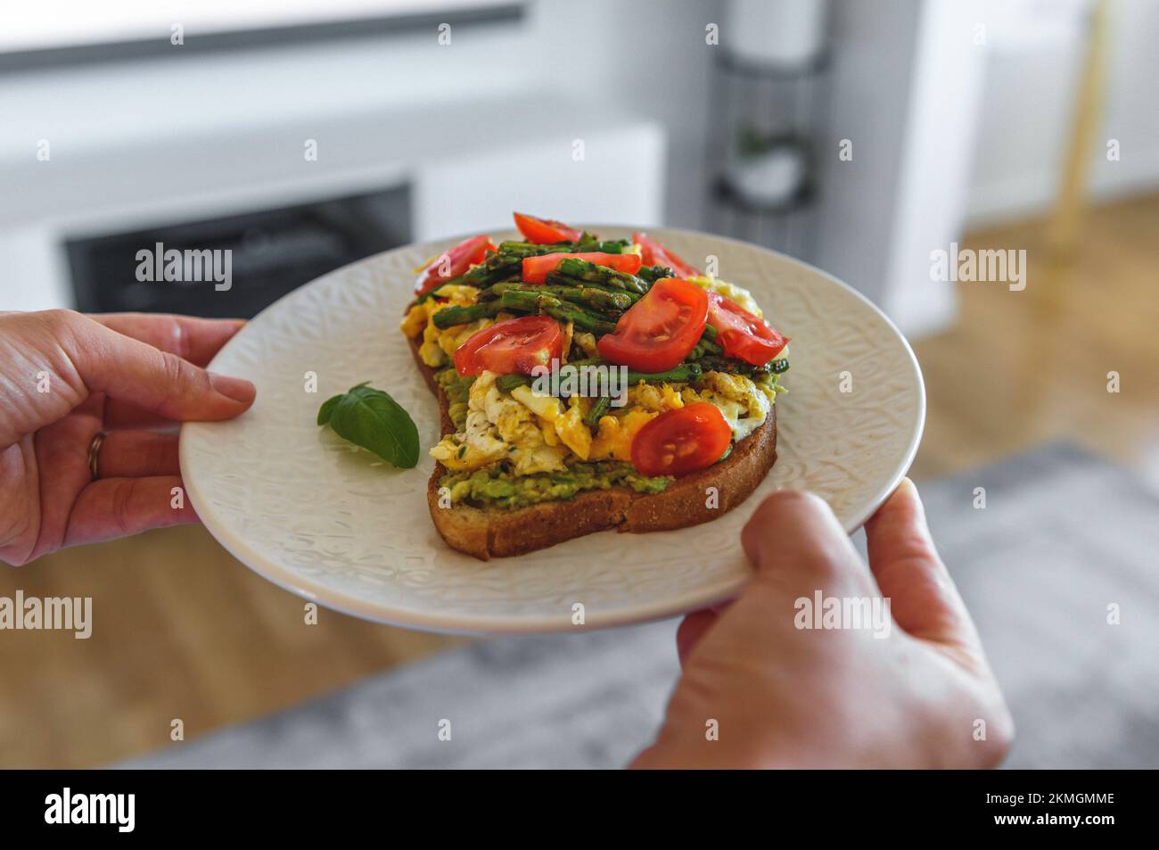 A Close up of hands holding plate with avocado toast with vegetables ...