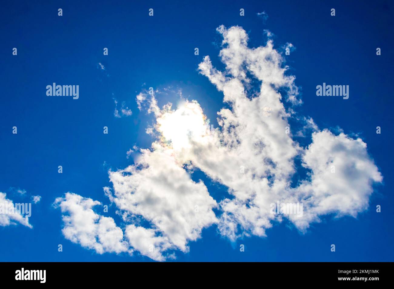 The sun comes out from behind the clouds with blue sky background in ...