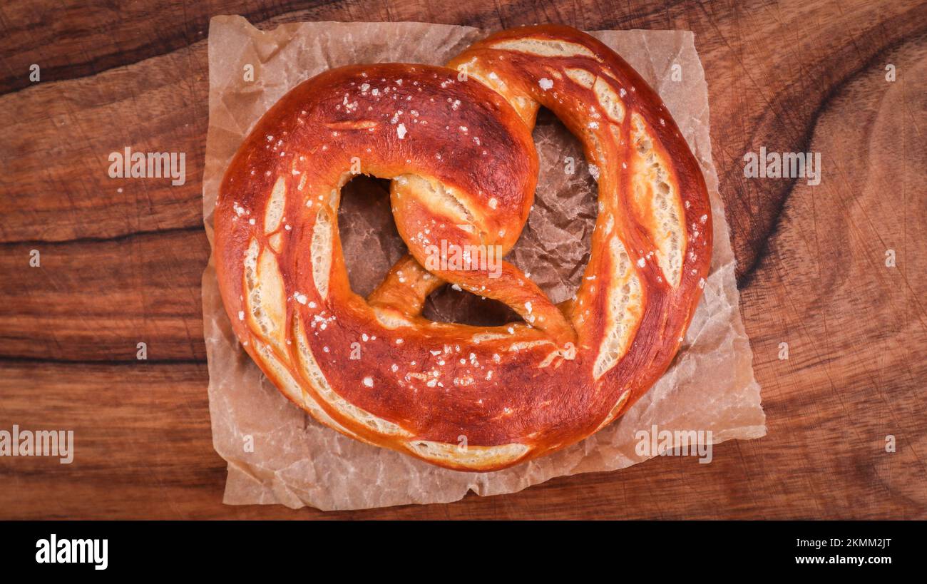 A freshly baked pretzel on a paper on a wooden background Stock Photo ...
