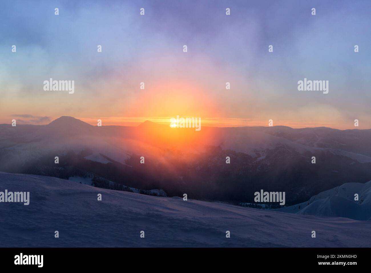 Bright orange sunrise of the sun disk in the snowy mountains. Marmarosy ...
