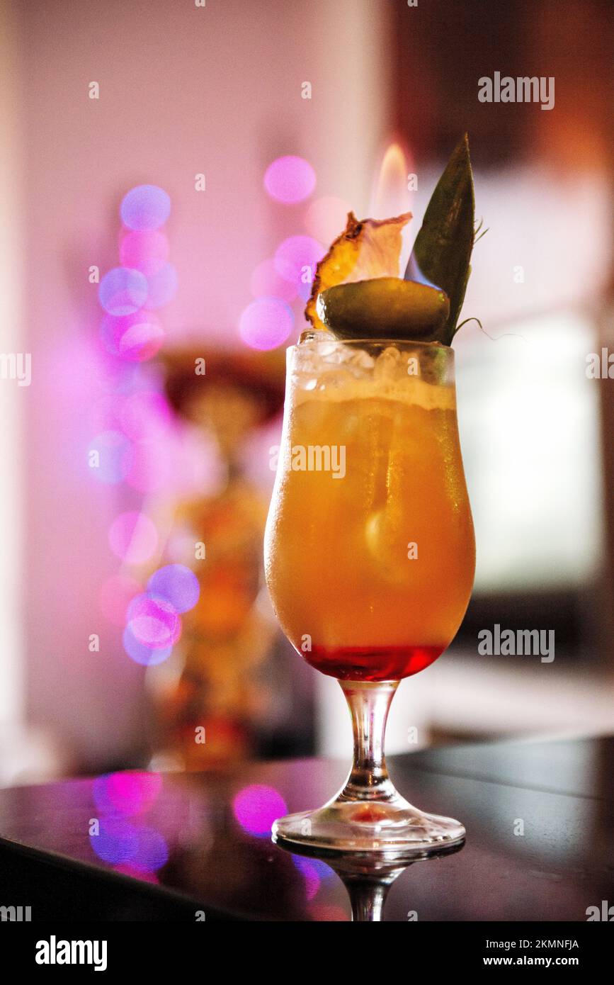 A vertical shot of a glass of cocktail on a table with colorful bokeh ...