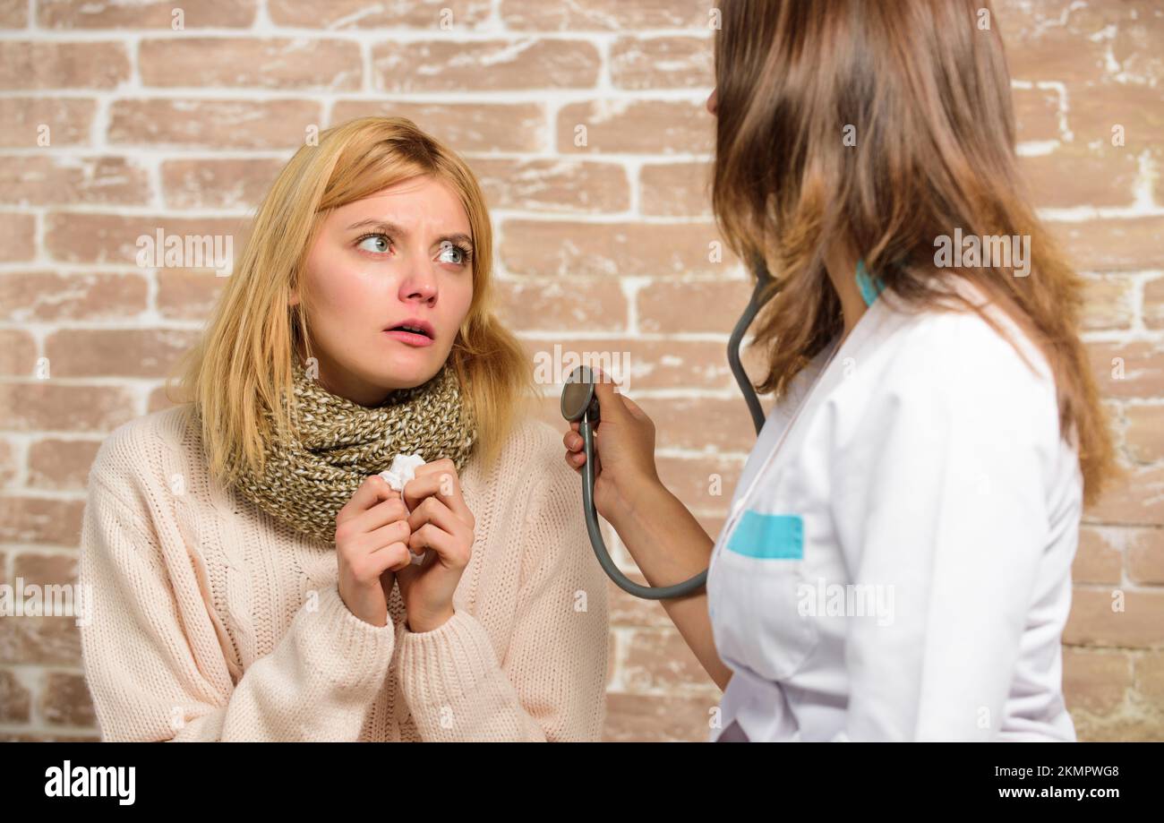 Girl in scarf hold tissue while doctor examine her. Cold and flu ...