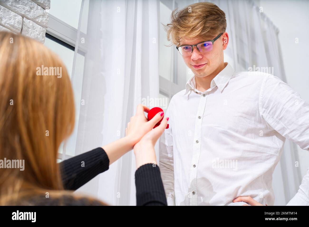 Embarrassing moment. Young woman holding box with engagement ring ...