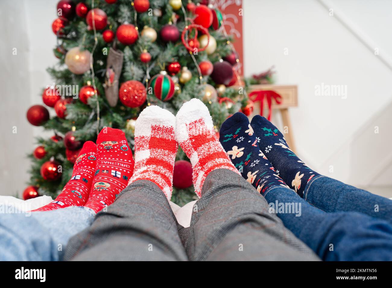 human feet on bed in christmas socks on background of christmas tree ...