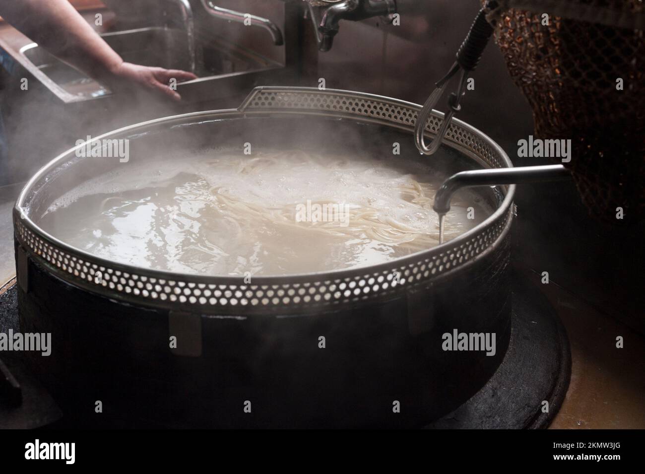 Noodles are cooked in simmering kettles over a wood fire in the ...
