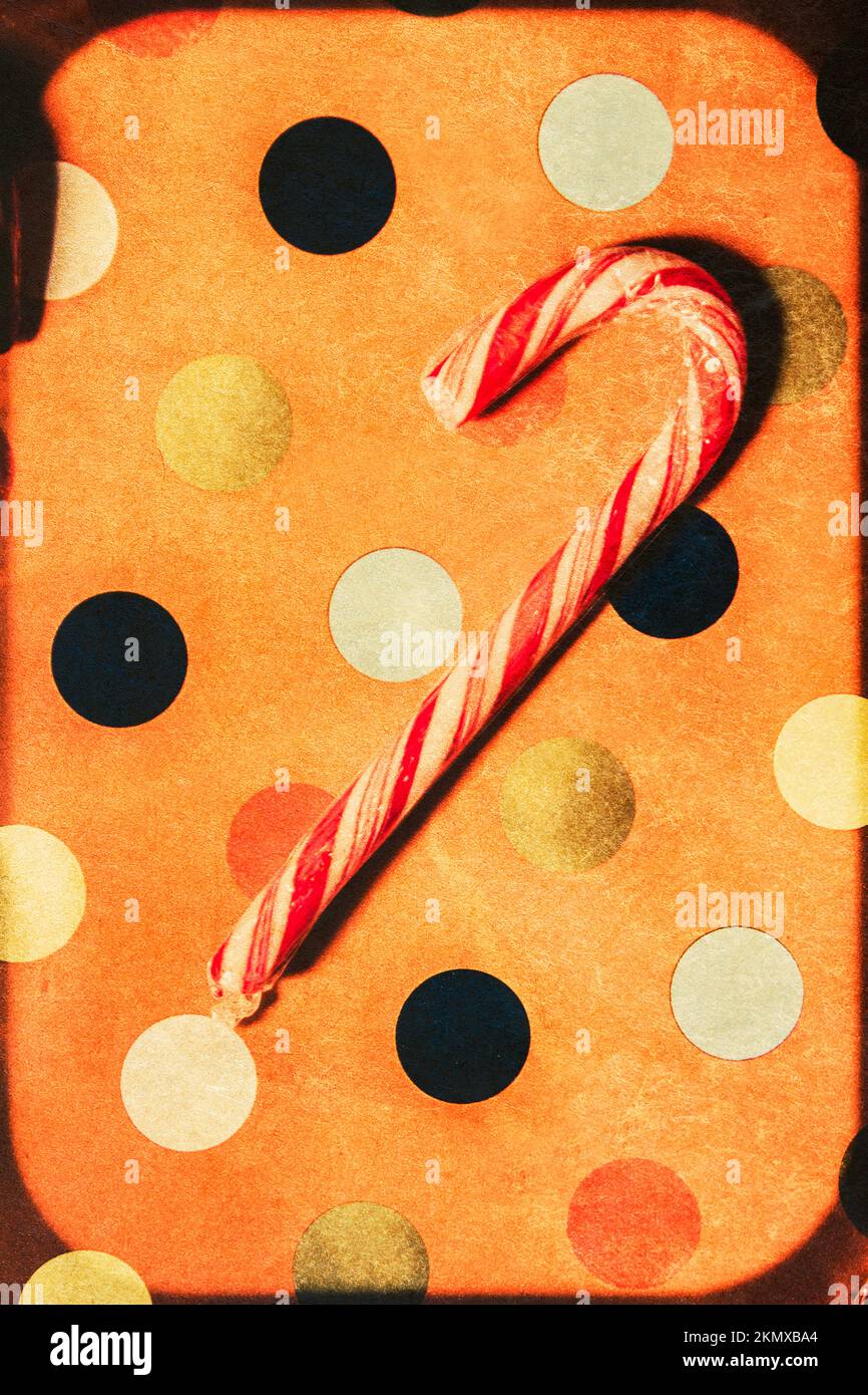 Old-fashioned still on a Christmas candy cane on bordered dot backdrop ...