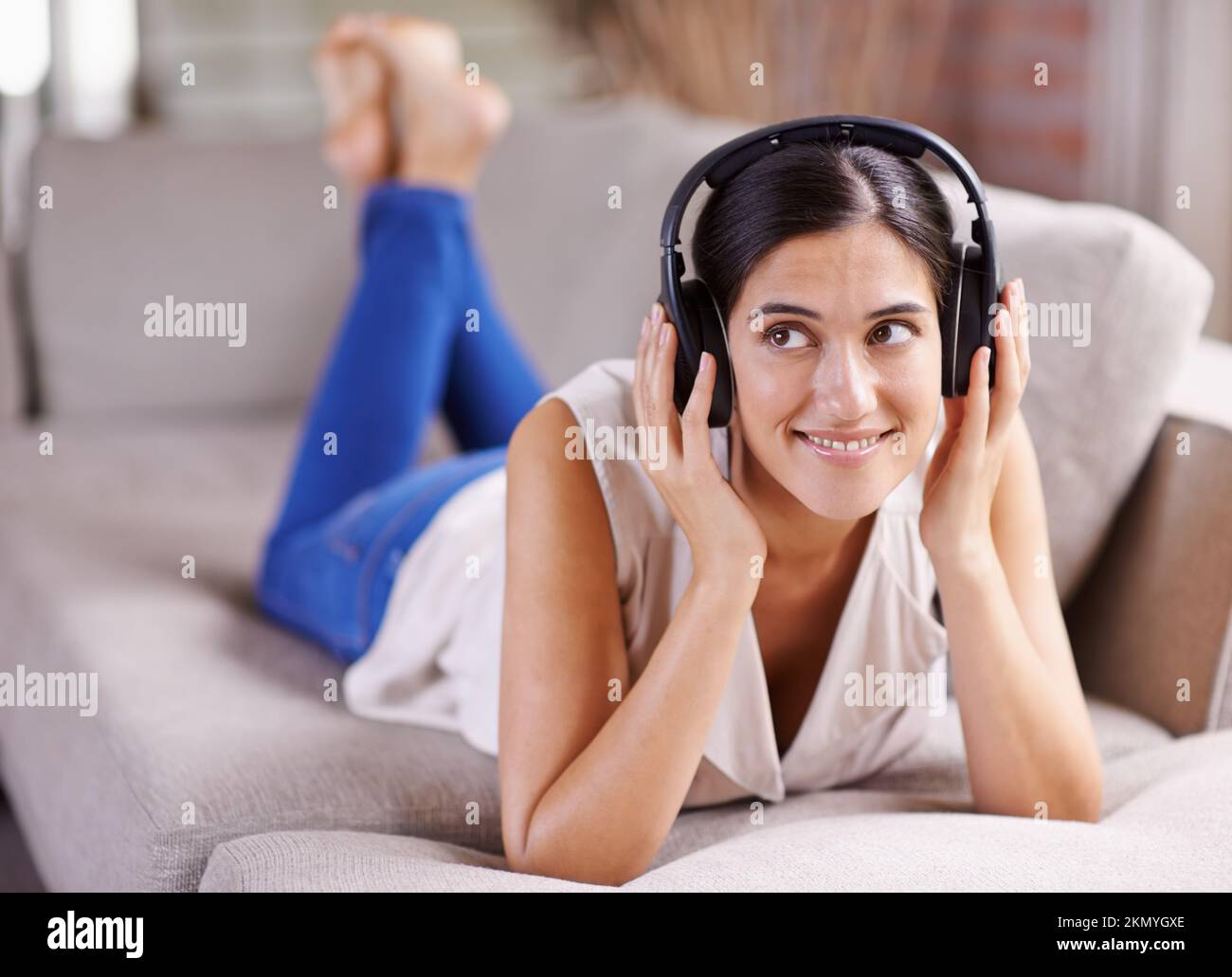 Getting into the beats. a young woman listening to music while relaxing ...