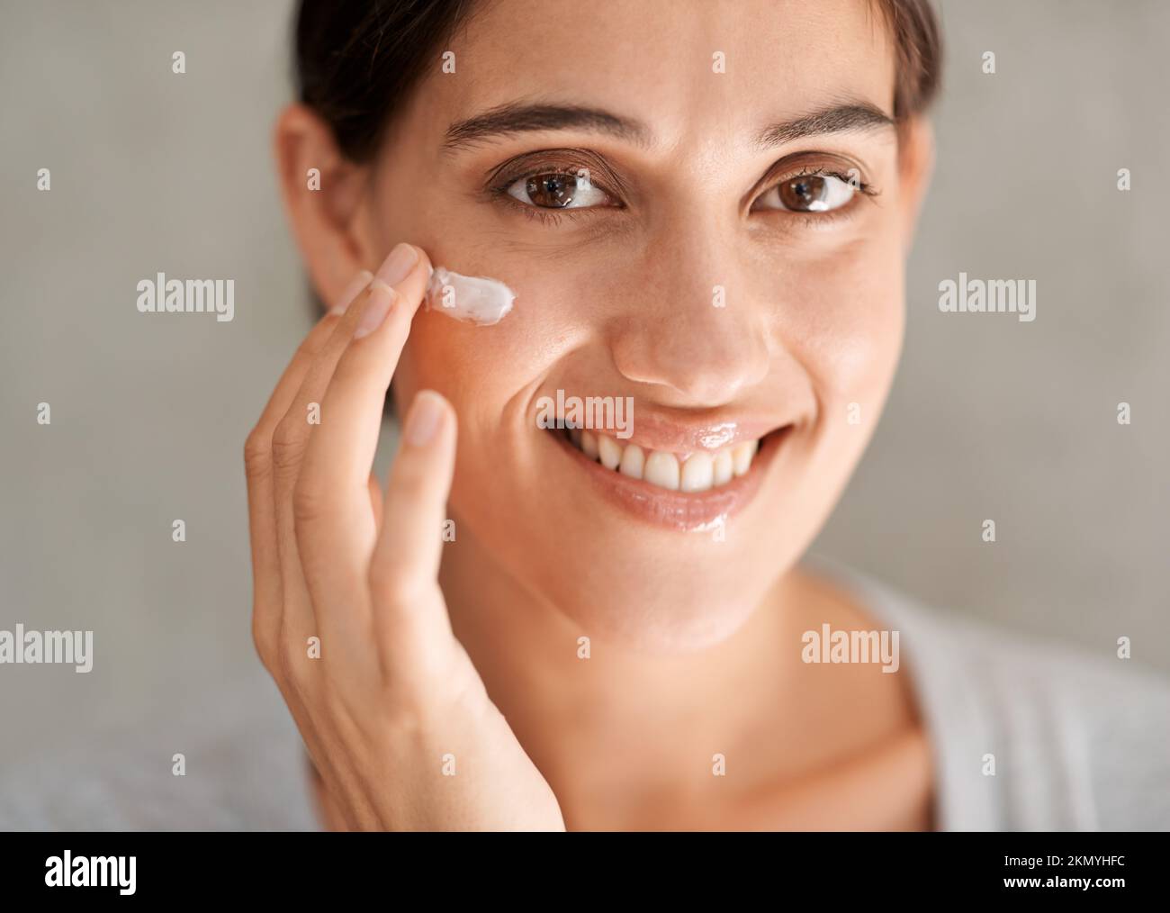 Taking care of her skin. a beautiful woman applying moisturizer to her ...