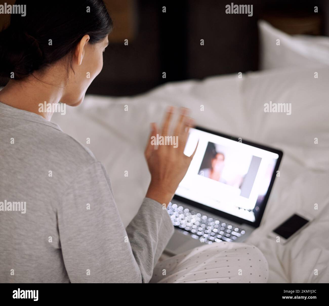 Late night chat session. A young woman working on her laptop in bed ...
