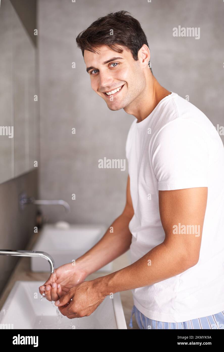 Good hygiene keeps him healthy. Portrait of a young man washing his ...