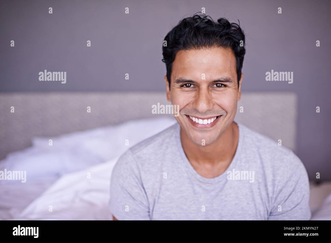 Waking up with a smile should be a good sign. a young man smiling in ...