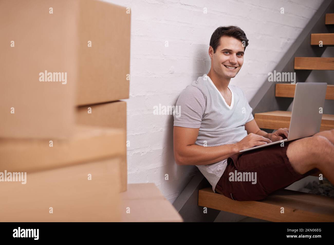 Sending my last email in my old home. A happy young man using his ... Sending my last email in my old home. A happy young man using his ...