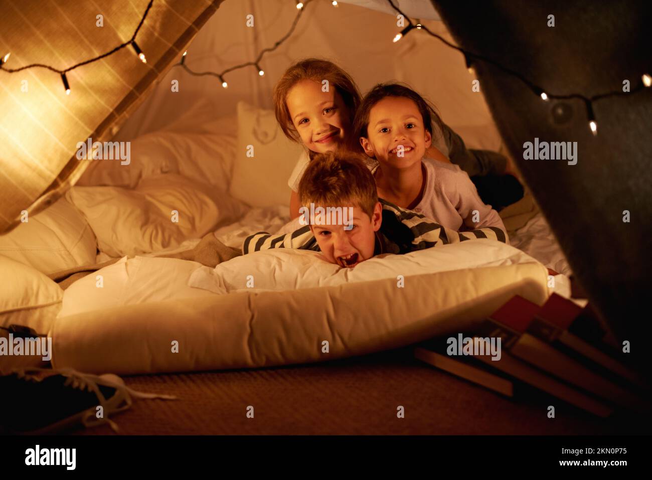Playful little ones. three young children in a blanket fort Stock Photo ...