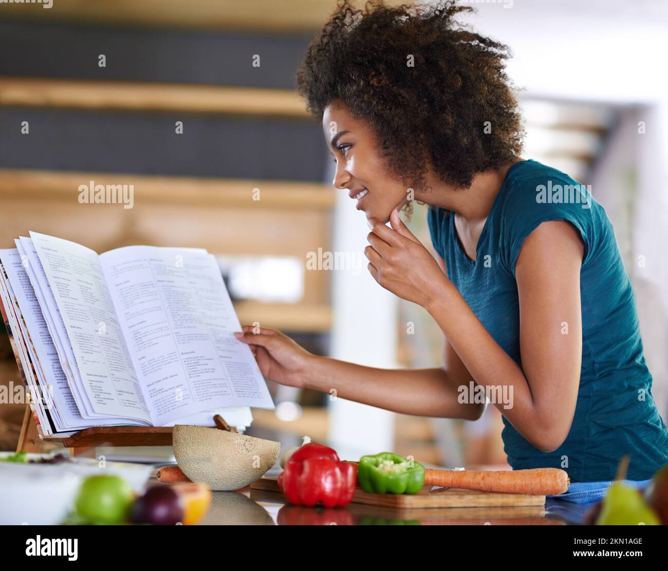 This looks like a good recipe. A young woman cooking from a recipe book ...