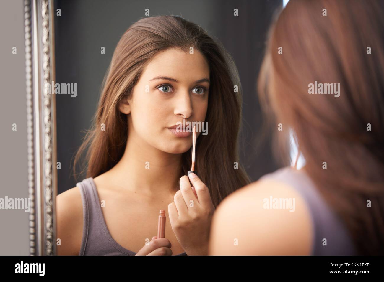 Adding some shine to her lips. a young woman putting on lipgloss in ...