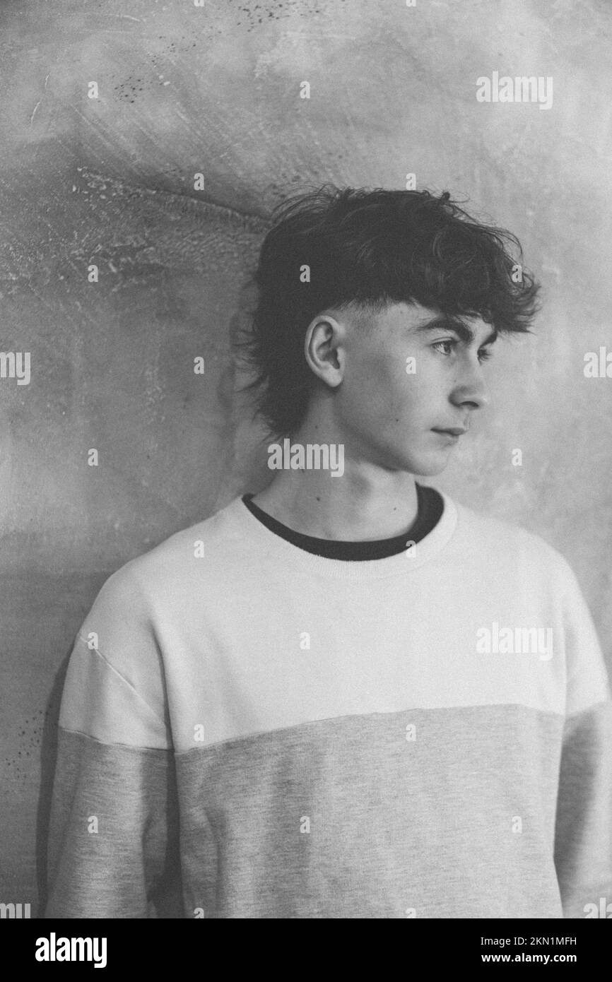 A vertical grayscale of a young male with styled hair looking away on ...